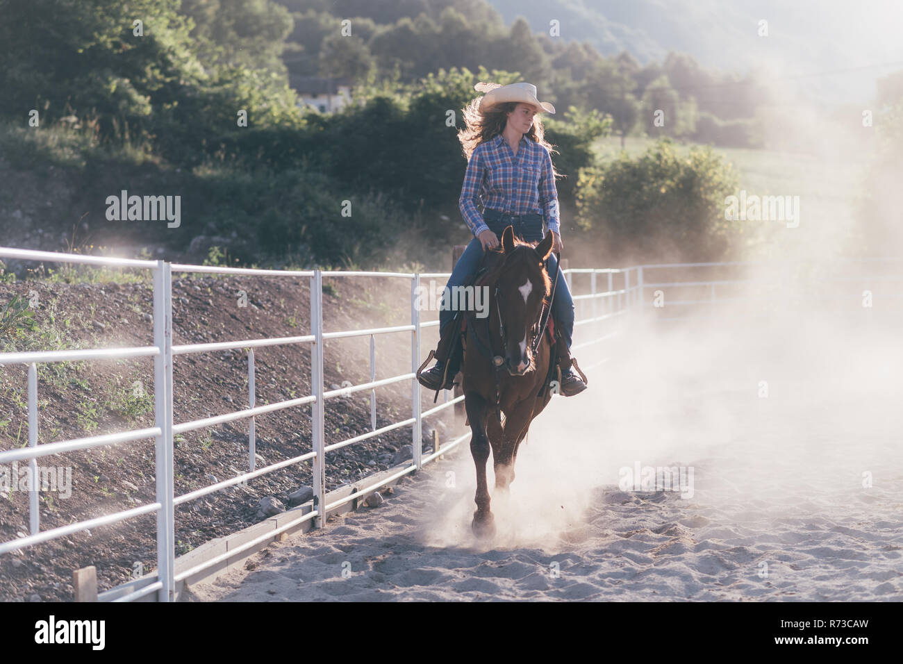 Cowgirl horse riding in dusty equestrian arena, Primaluna, Trentino ...