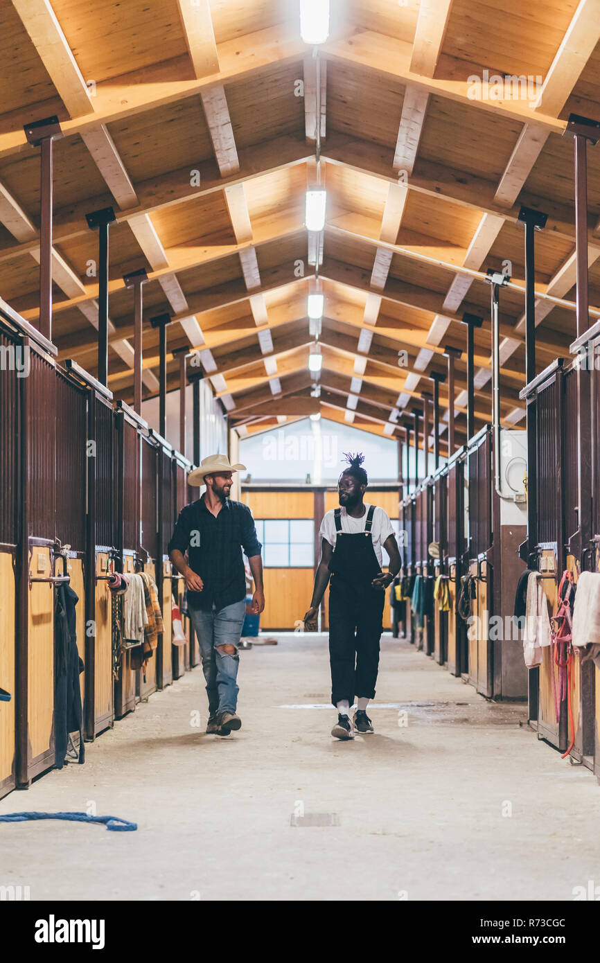 Cowboy and cool young man walking in stable block Stock Photo - Alamy