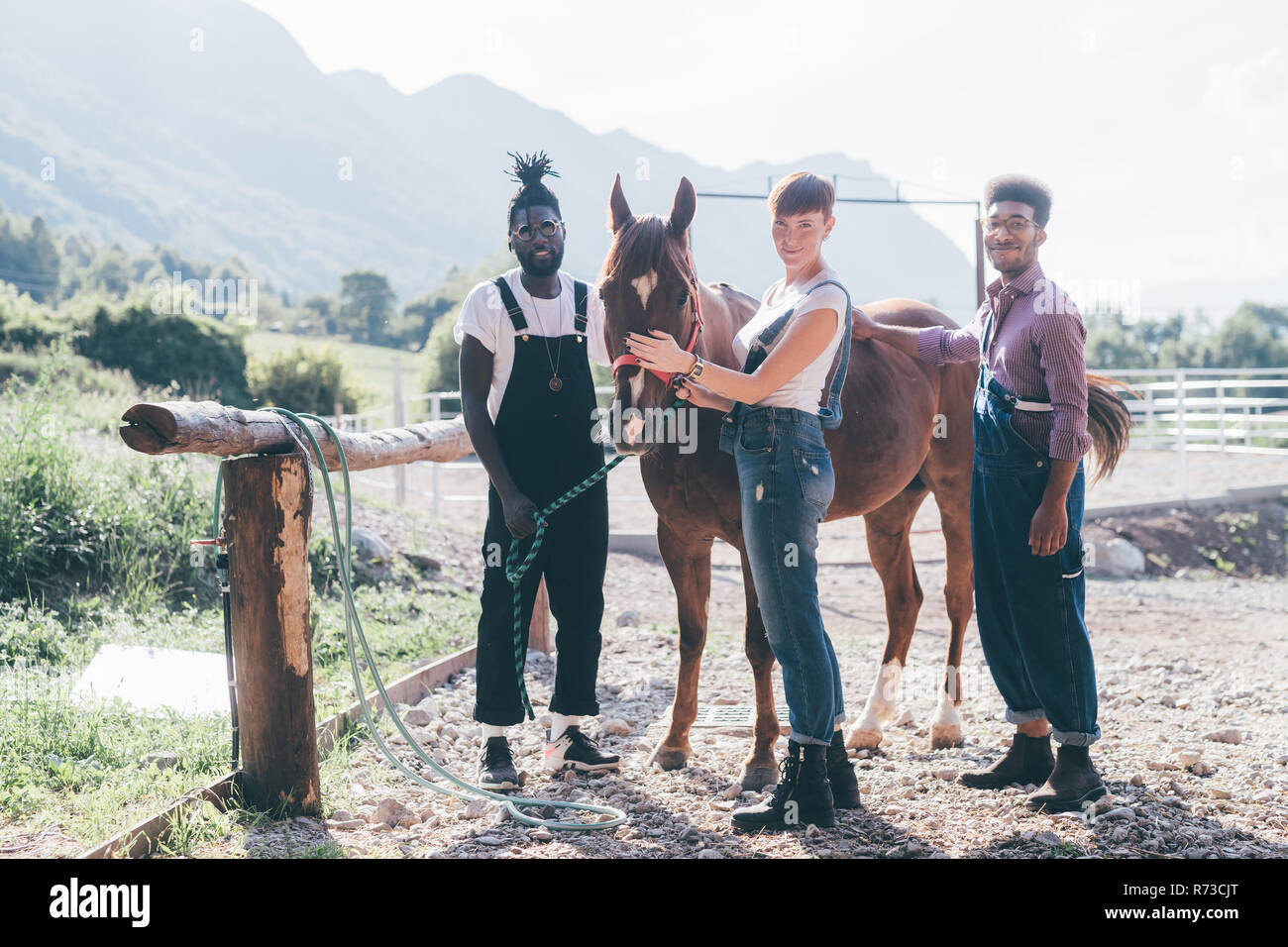 Young woman and men bonding with horse in rural equestrian arena ...