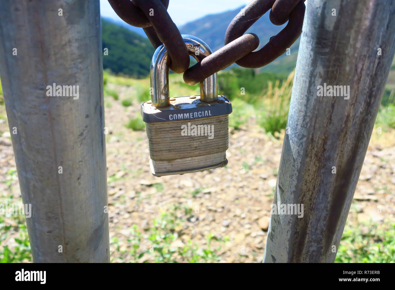 A metal gate chained shut by a rusty chain and a large padlock Stock ...