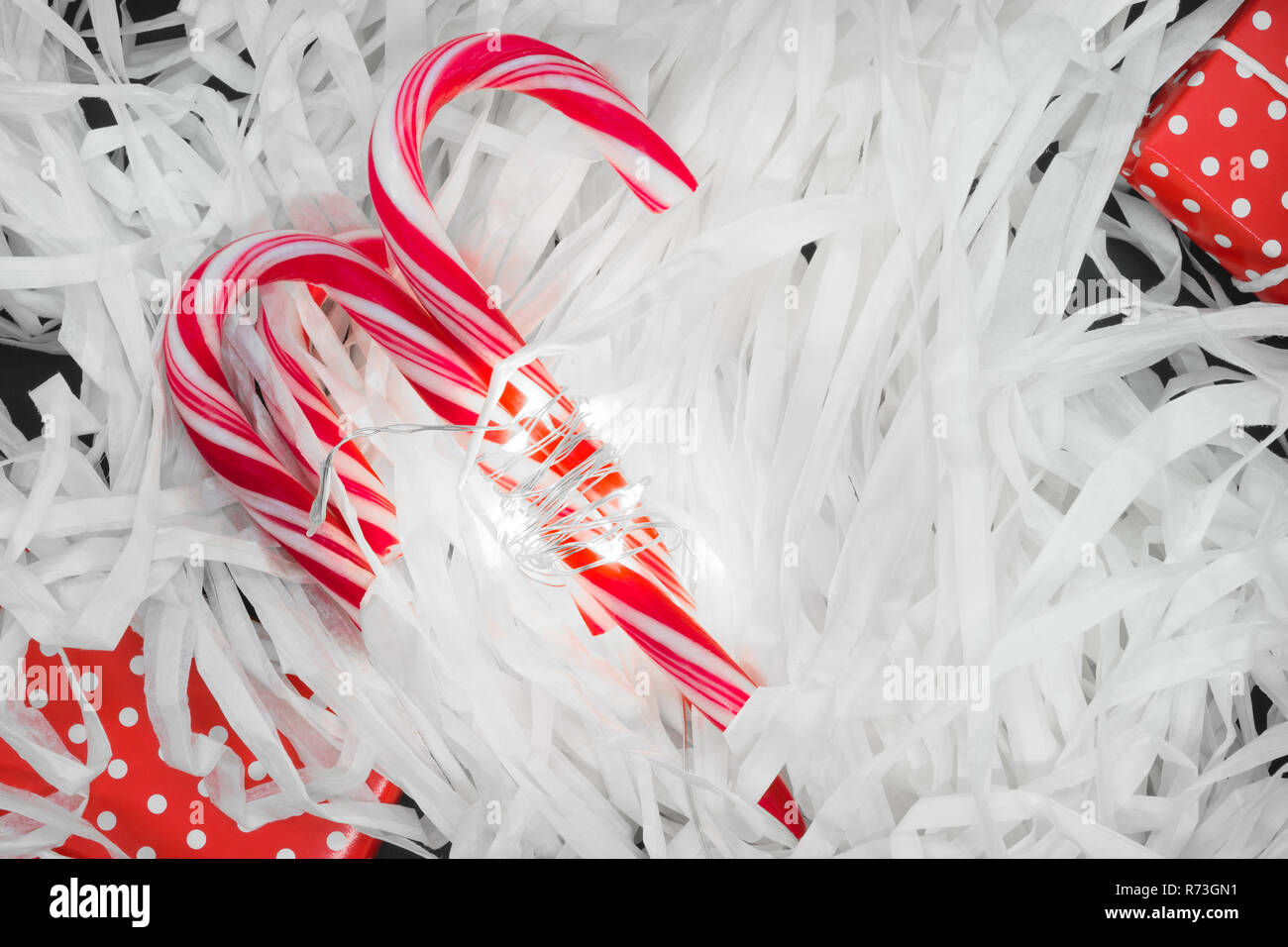 Christmas candy canes and red gift boxes illuminated by garland and ...