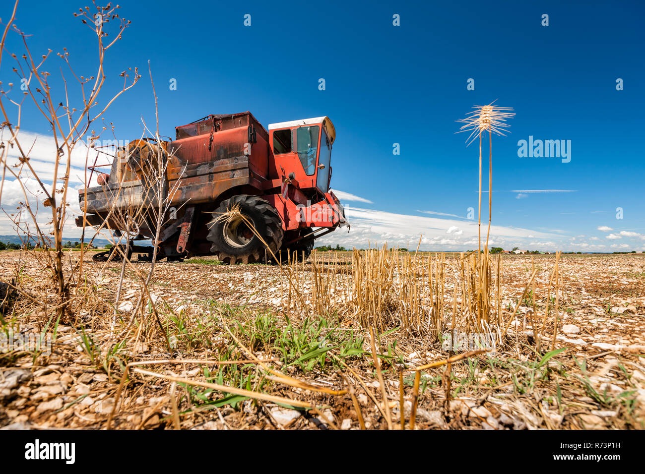 Old burned agriculture combines in a flattened grainfield under a blue ...