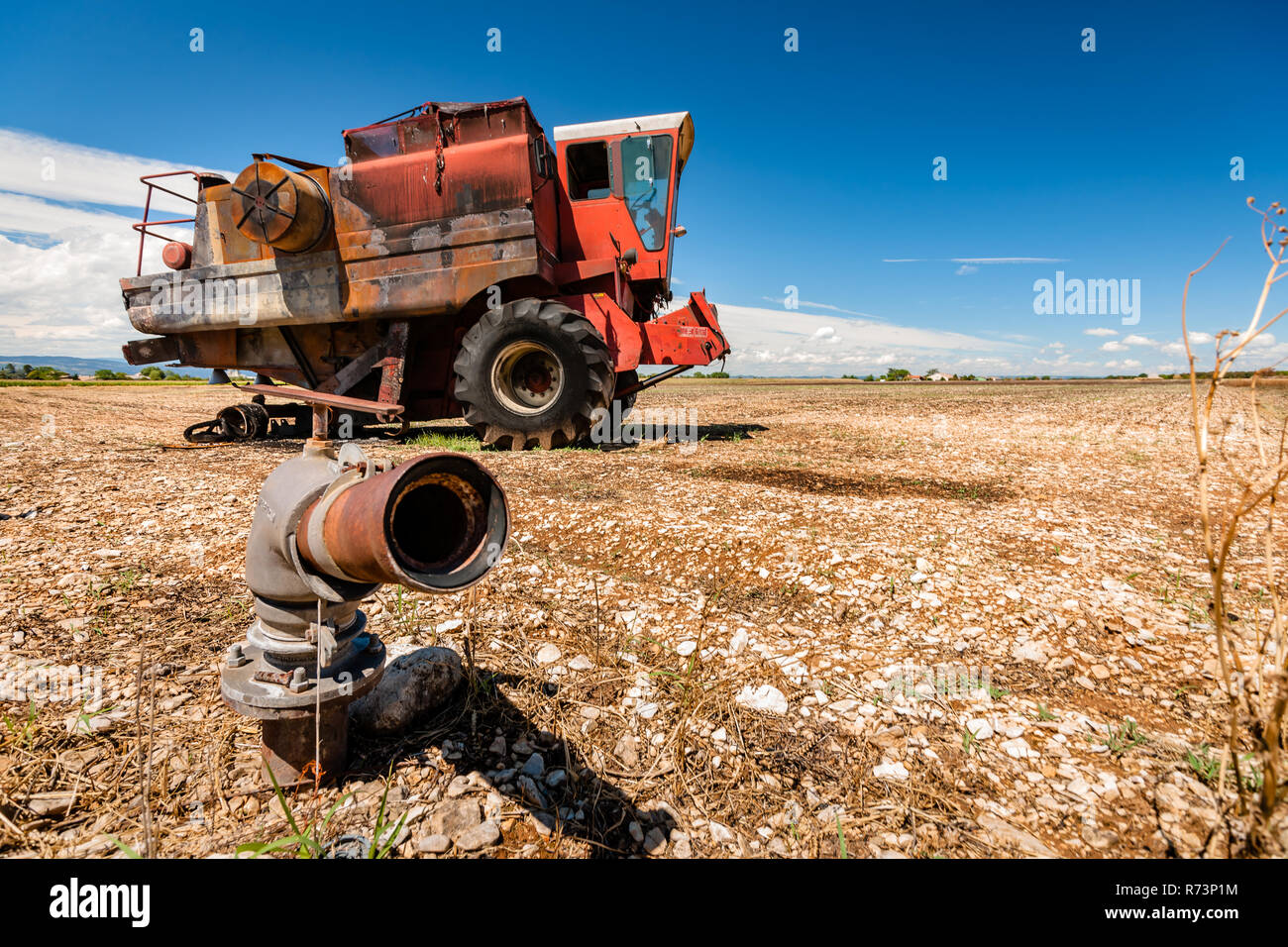 Old burned agriculture combines in a flattened grainfield under a blue ...