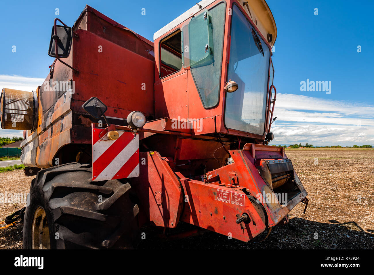 Old burned agriculture combines in a flattened grainfield under a blue ...
