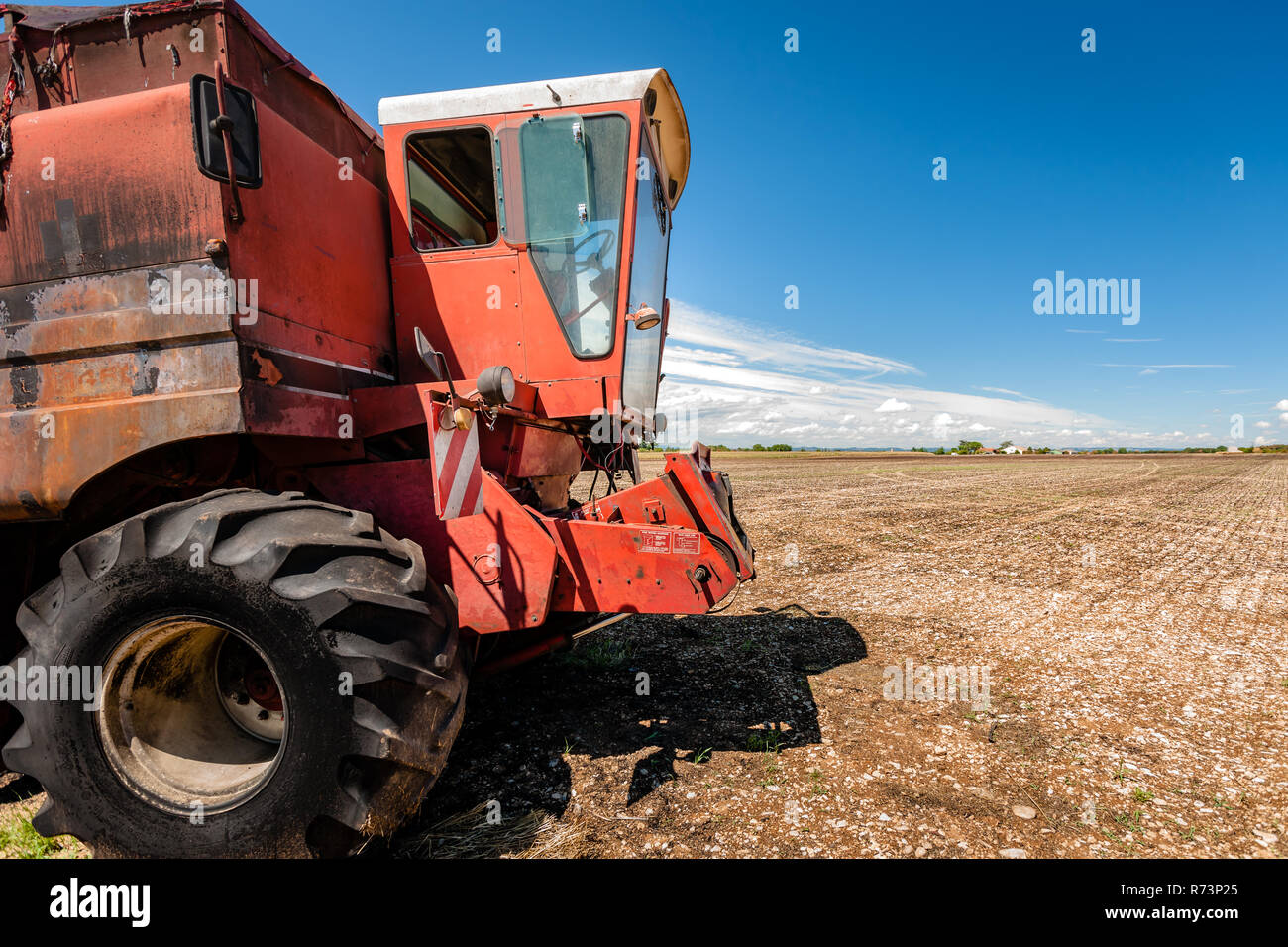 Old burned agriculture combines in a flattened grainfield under a blue ...