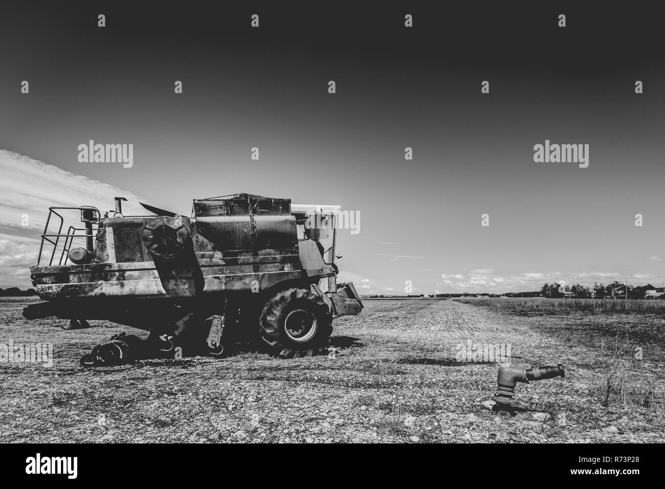Old burned agriculture combines in a flattened grainfield under a blue ...