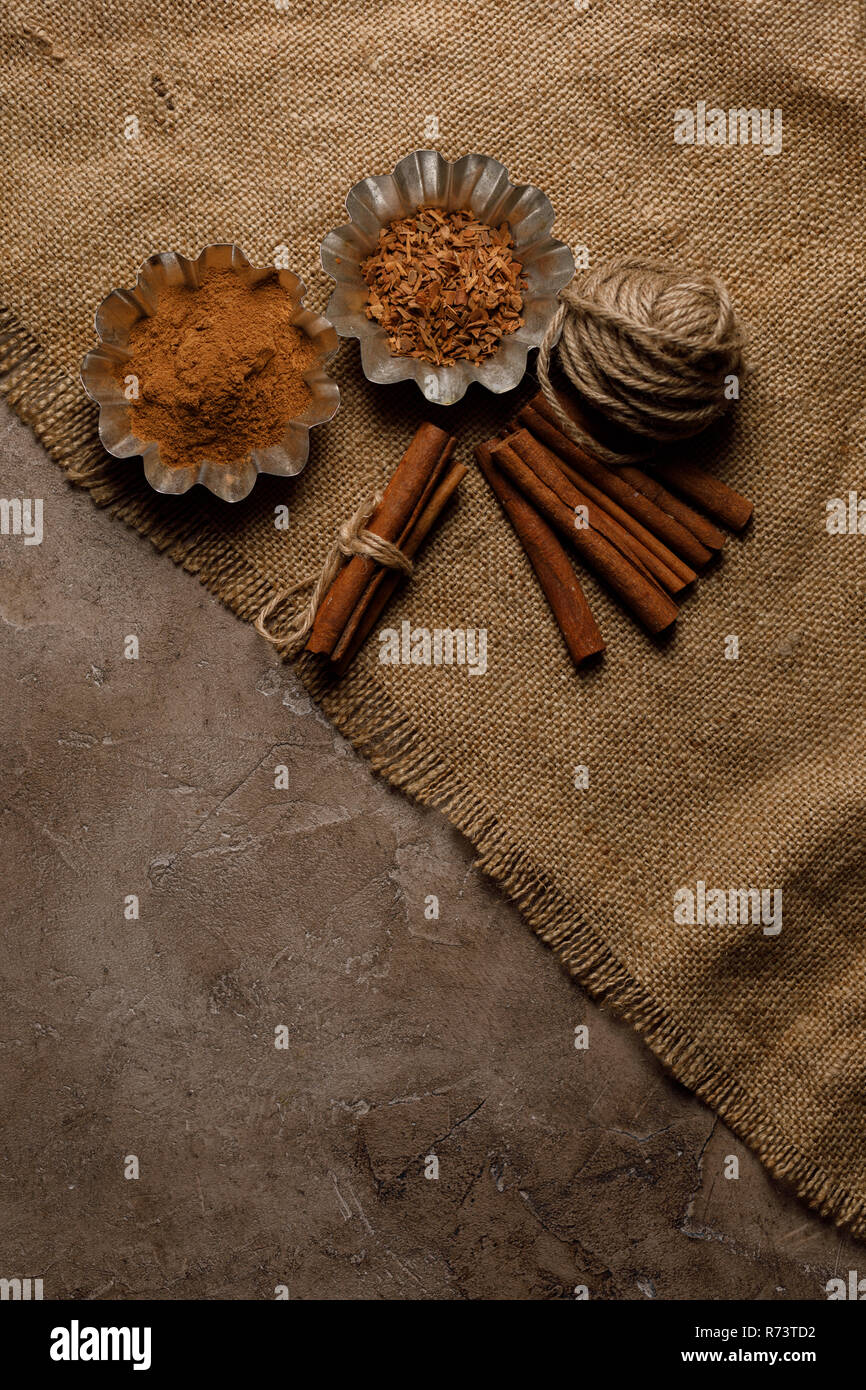 Finely chopped cinnamon and cinnamon sticks on a textured background ...