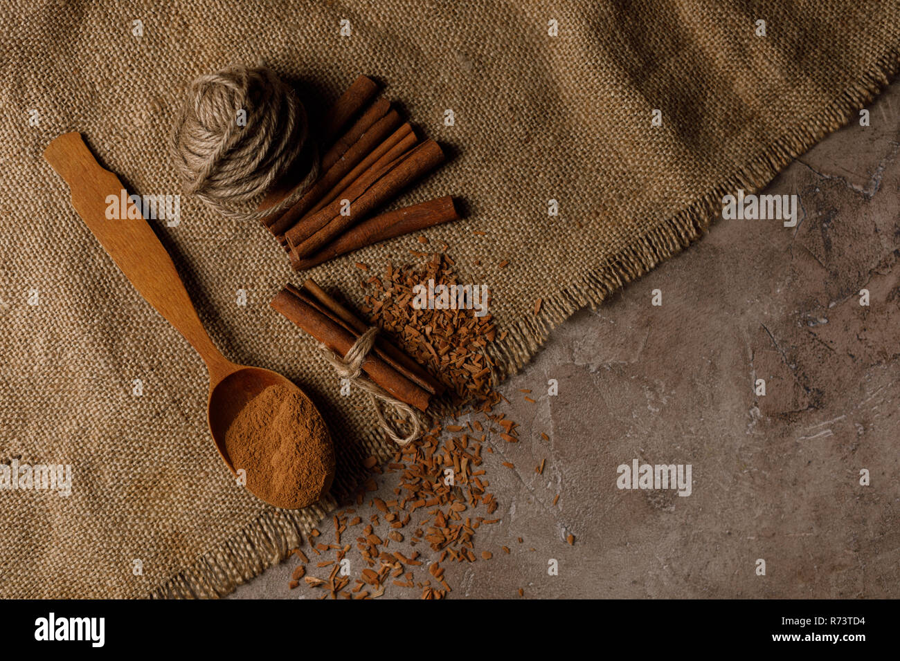 Finely chopped cinnamon in a wooden spoon and cinnamon sticks on a ...