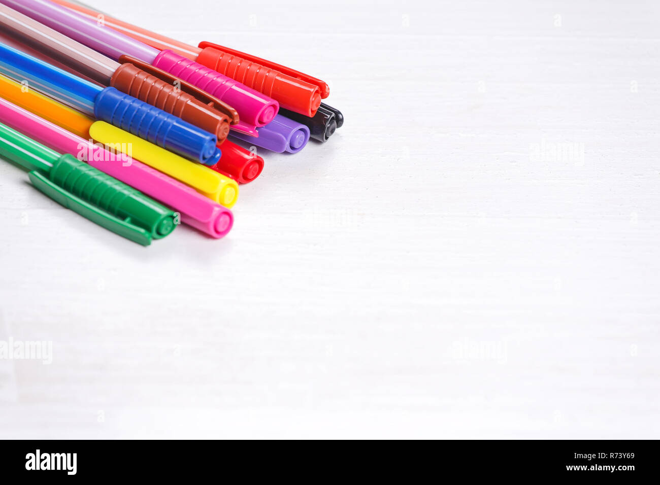 Colorful pens on natural white wooden background. Arranged in a stack ...