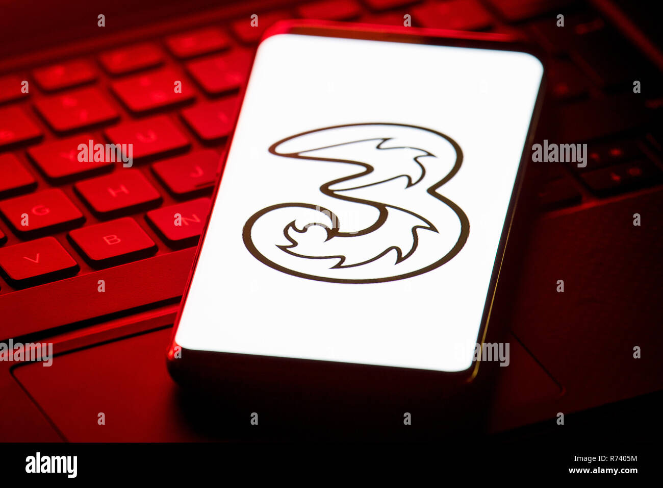 The logo of mobile phone network Three is displayed on the screen of a ...