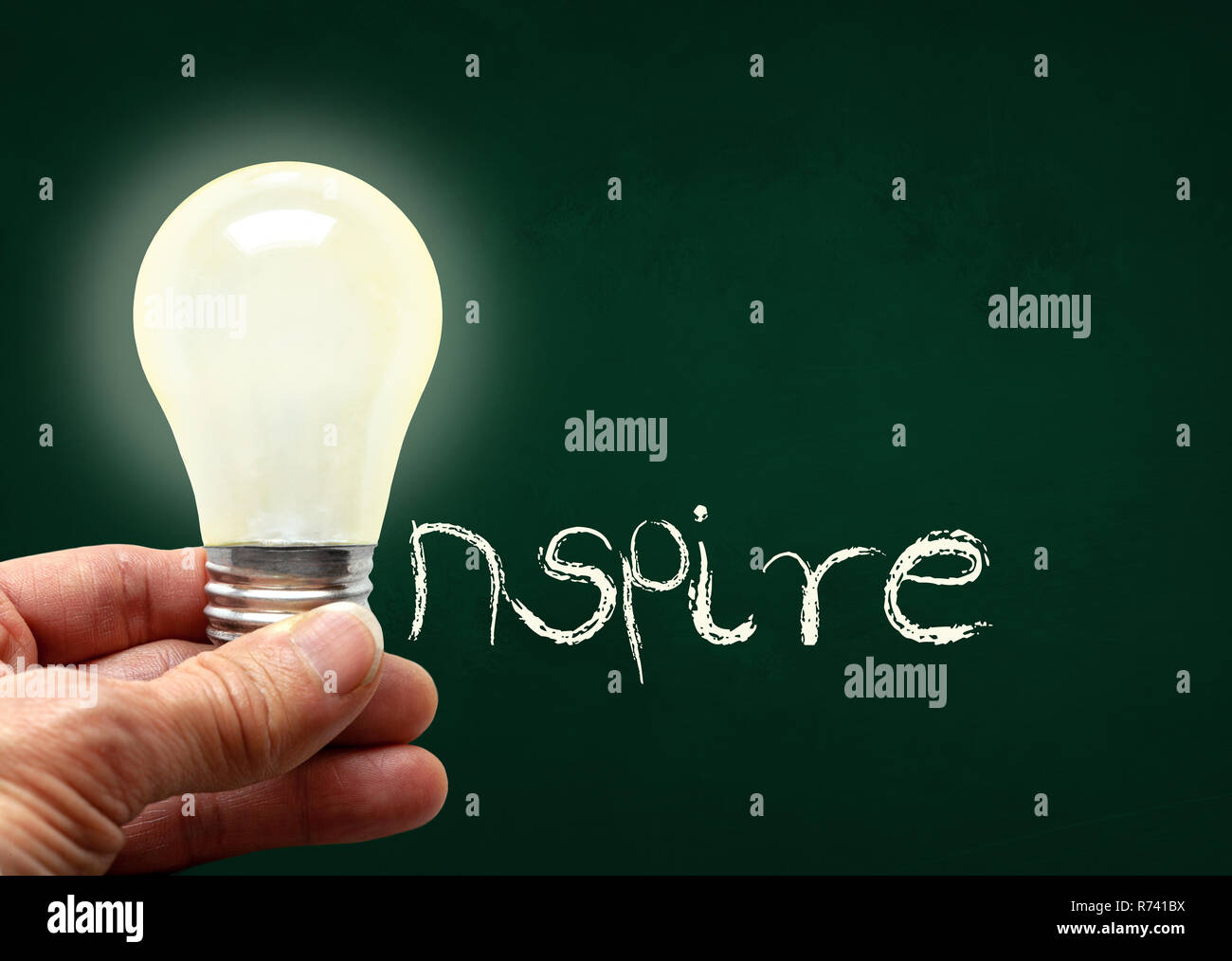 Man holding illuminated bulb with bare hands against chalkboard with ...