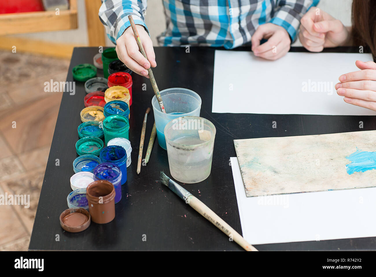 Young beautiful mother with boys son paint colors at home. Mom teaches ...