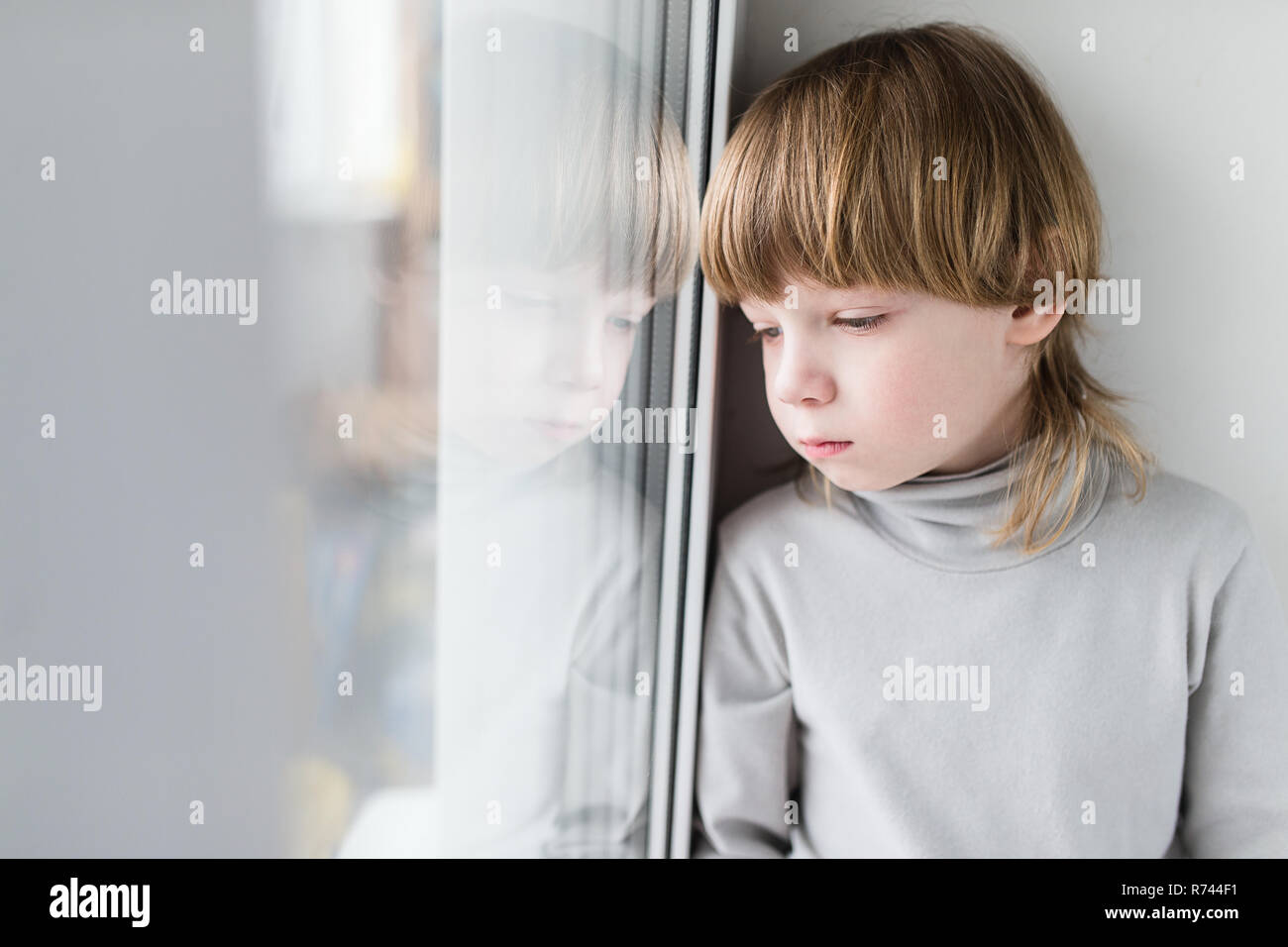 Sad child sitting on window and sad Stock Photo - Alamy