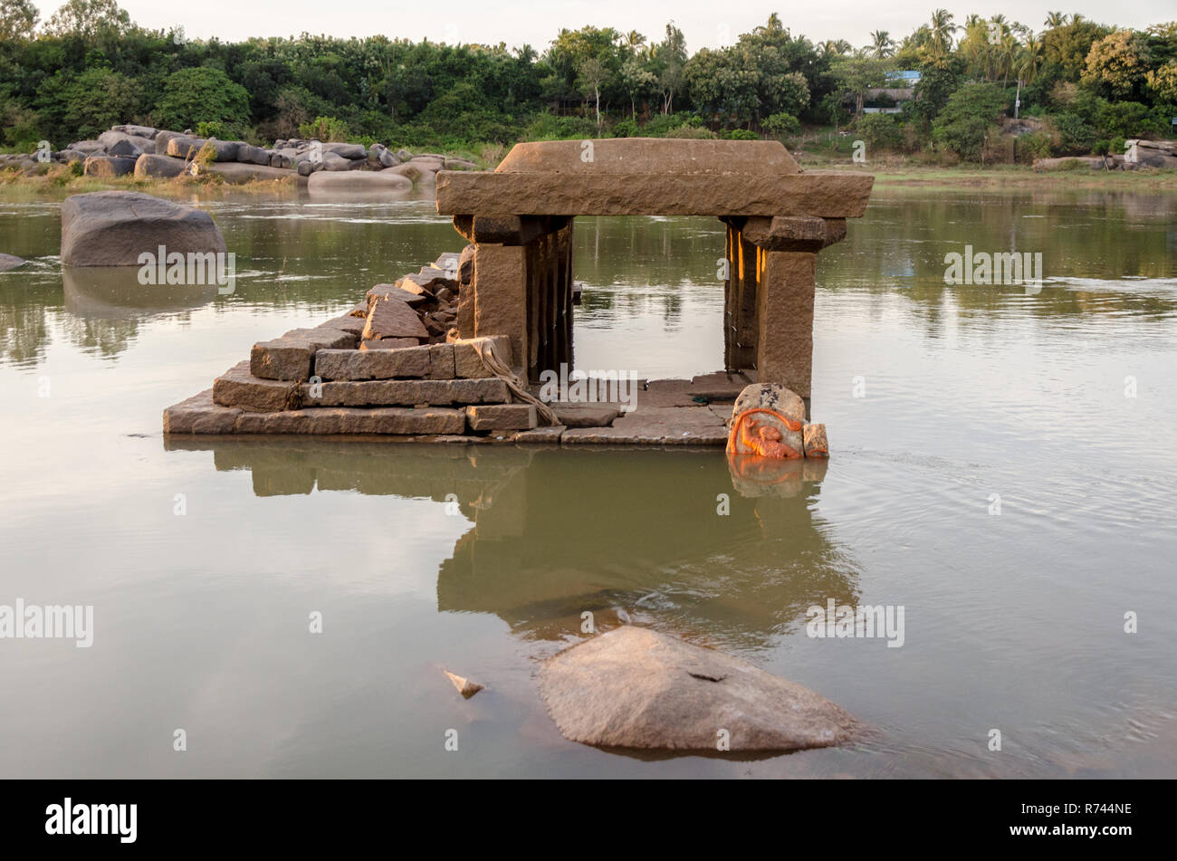 A half submerged stone temple structure with partially visible Hanuman ...