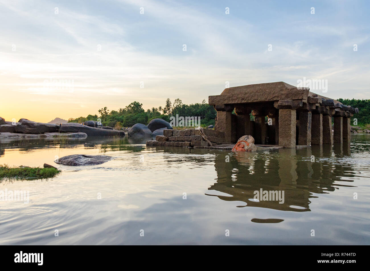 A half submerged stone temple structure with partially visible Hanuman ...