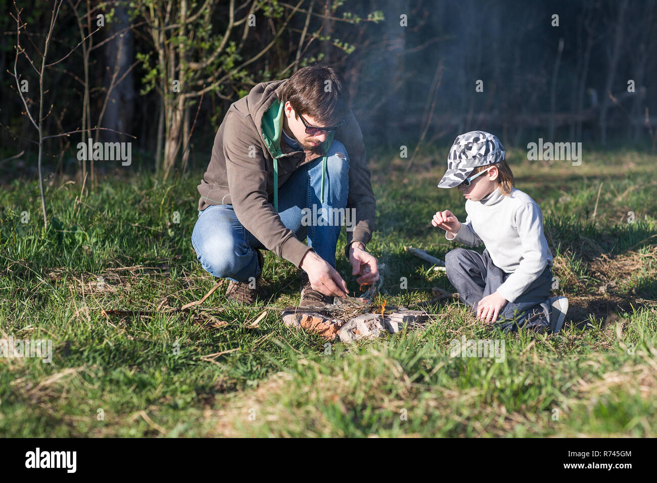 Dad with son kindle bonfire on a picnic in the woods. The concept of ...