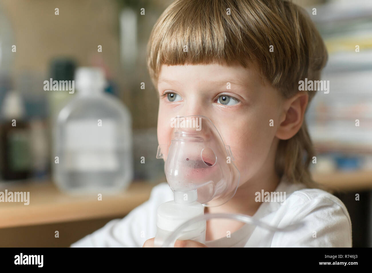 child holds a mask vapor inhaler. breathing through a steam nebulizer ...
