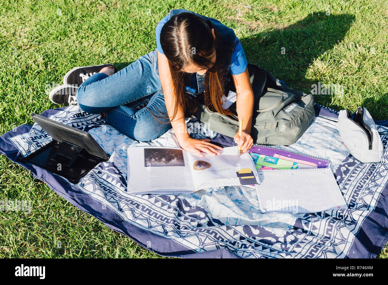 Girl doing homework on grass Stock Photo - Alamy