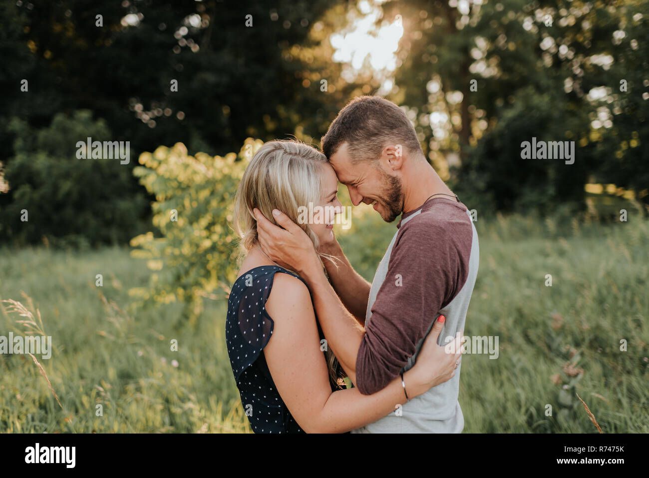 Romantic young woman and boyfriend face to face in field at sunset ...