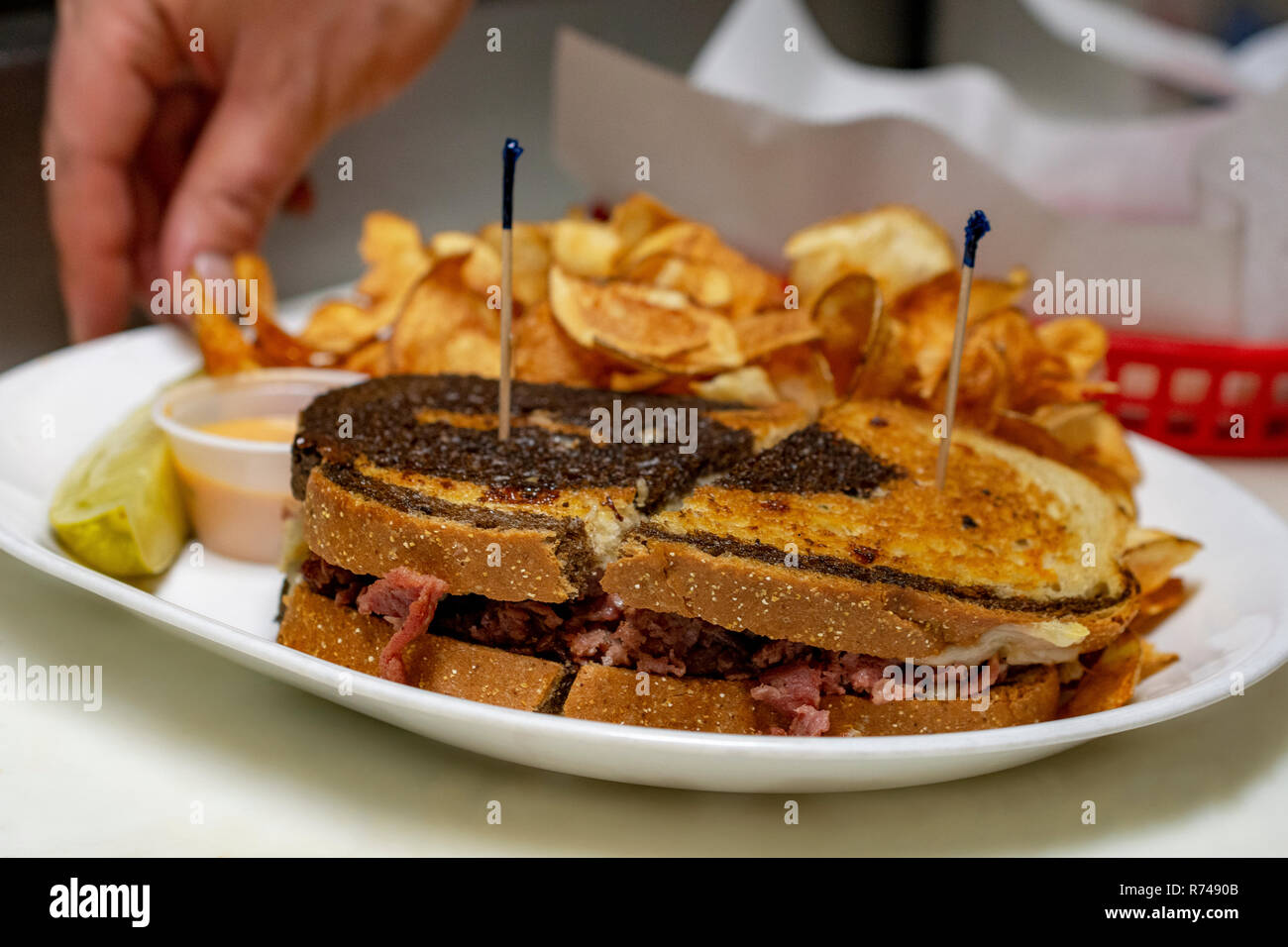Completed Reuben sandwich with potato chips and sauce with a dill ...