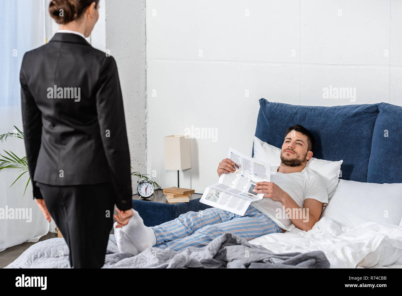 girlfriend standing in suit and boyfriend in pajamas with newspaper ...