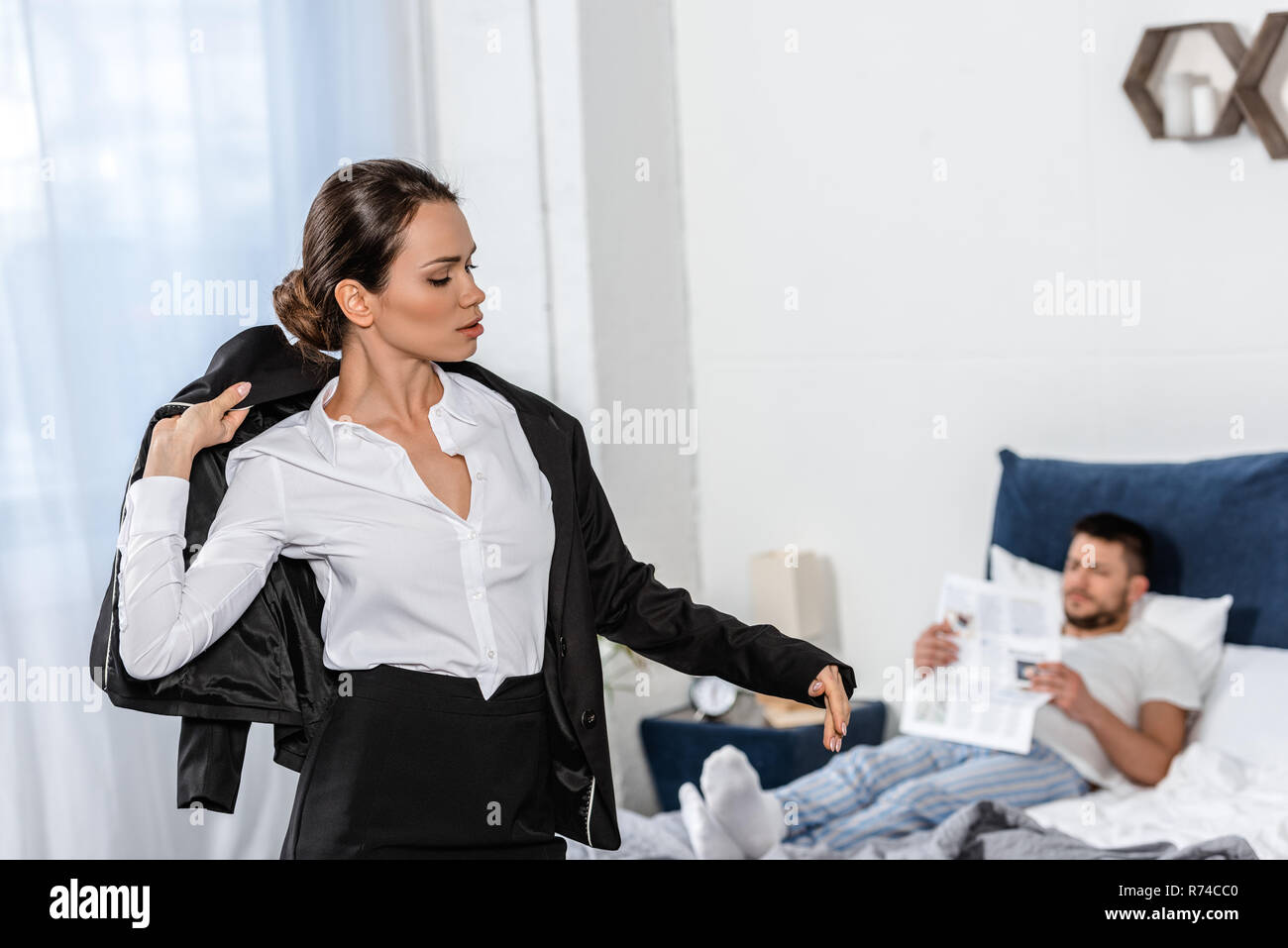 girlfriend wearing jacket and boyfriend in pajamas reading newspaper in ...