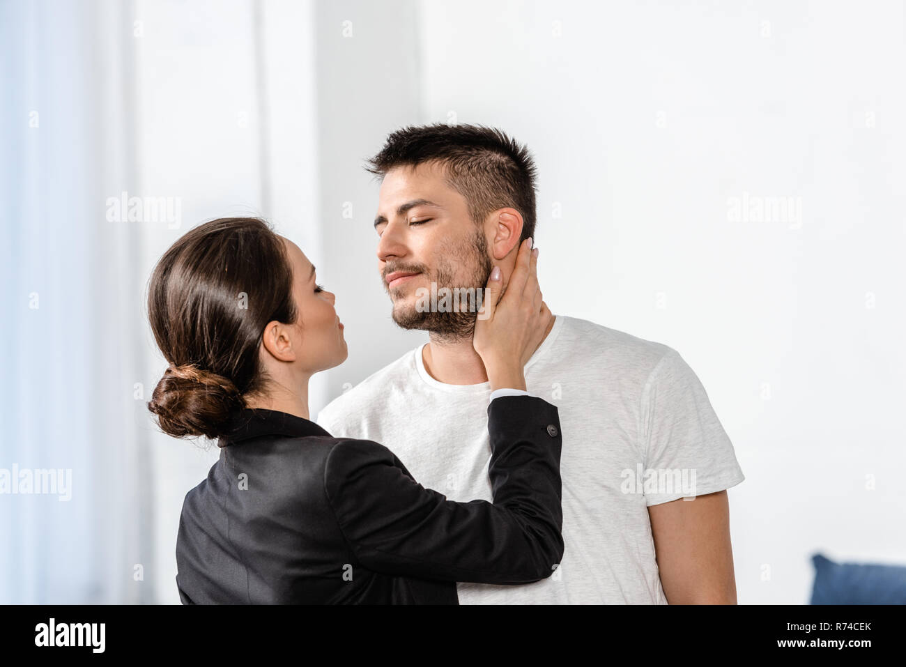 girlfriend in suit going to kiss boyfriend in pajamas in bedroom in ...