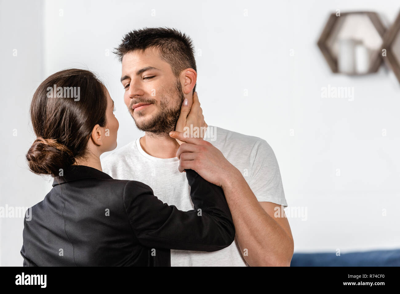 girlfriend in suit going to kiss boyfriend in pajamas in bedroom in ...