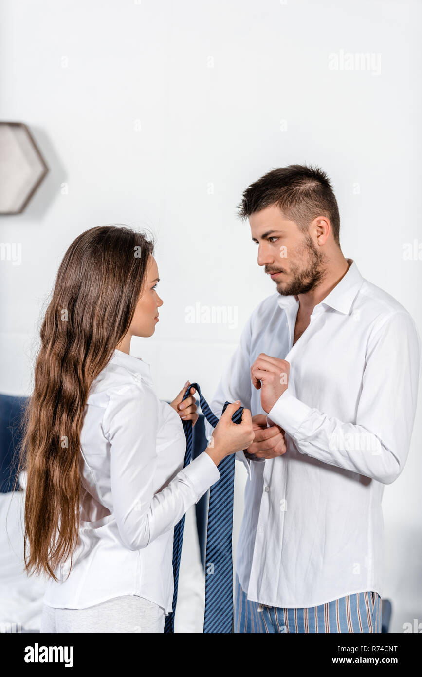 handsome boyfriend buttoning cuff, girlfriend holding his tie in ...