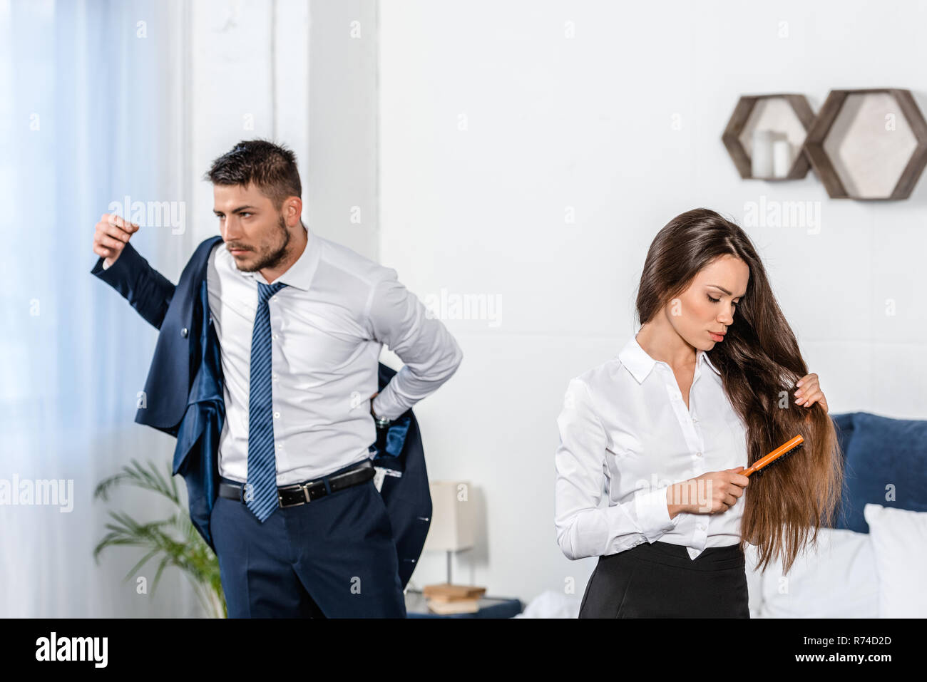 girlfriend combing hair and boyfriend wearing jacket in morning at ...