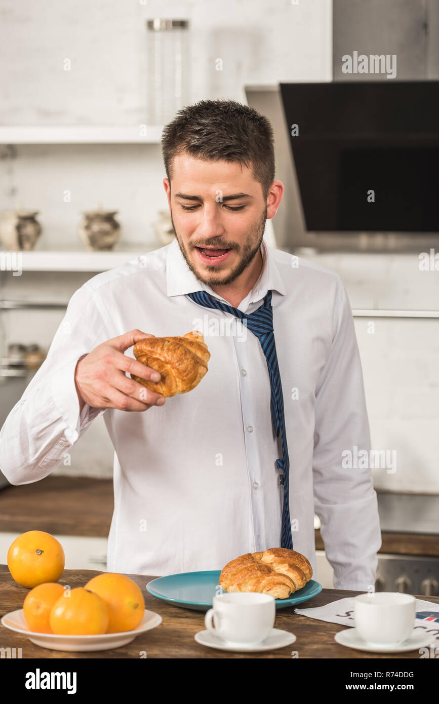 handsome man eating croissant in morning at kitchen Stock Photo - Alamy