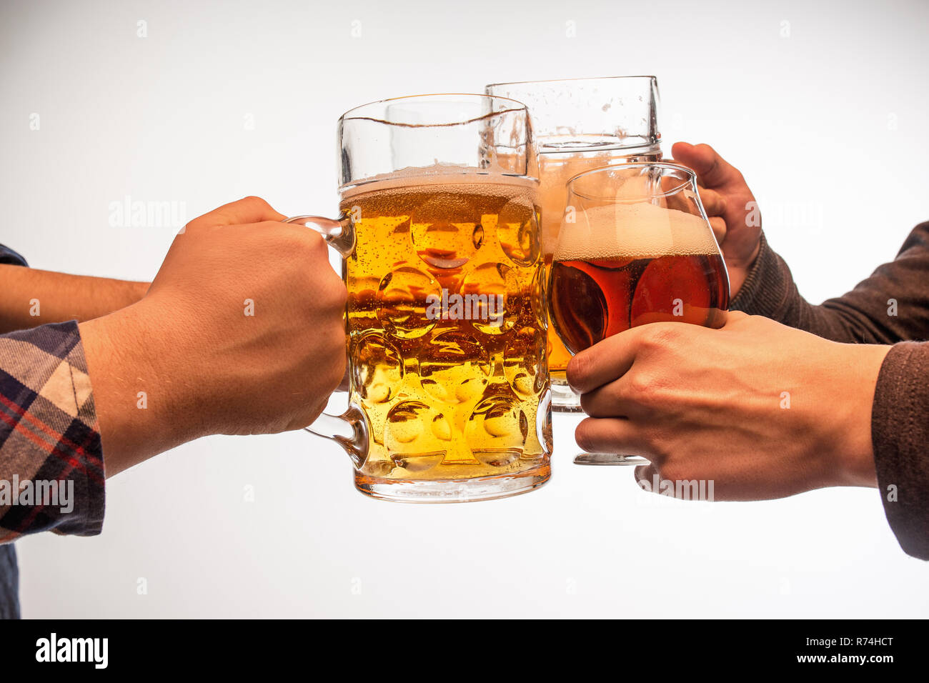 hands with mugs of beer toasting creating splash isolated on white ...