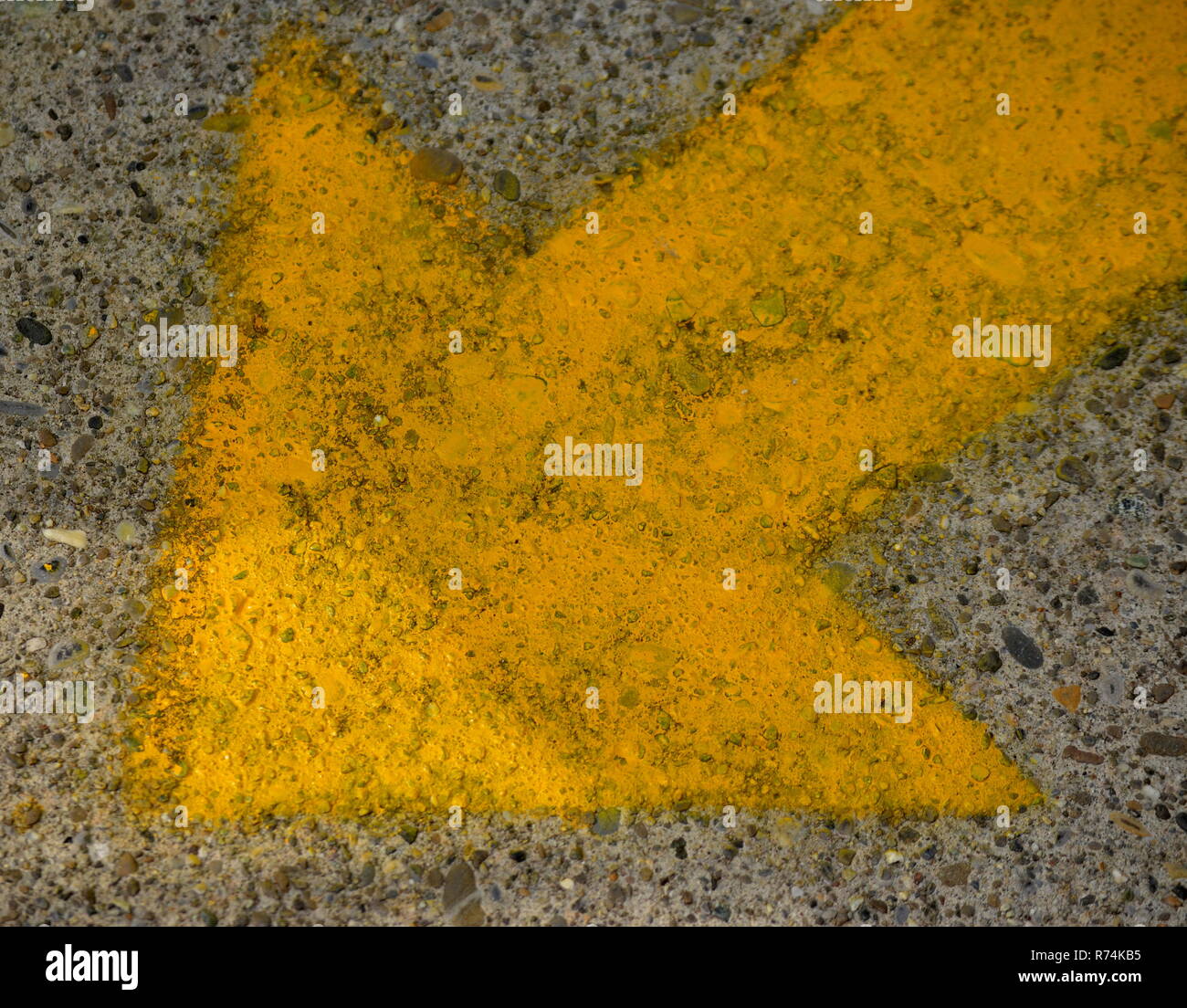 Painted yellow arrow on the concrete surface Stock Photo - Alamy
