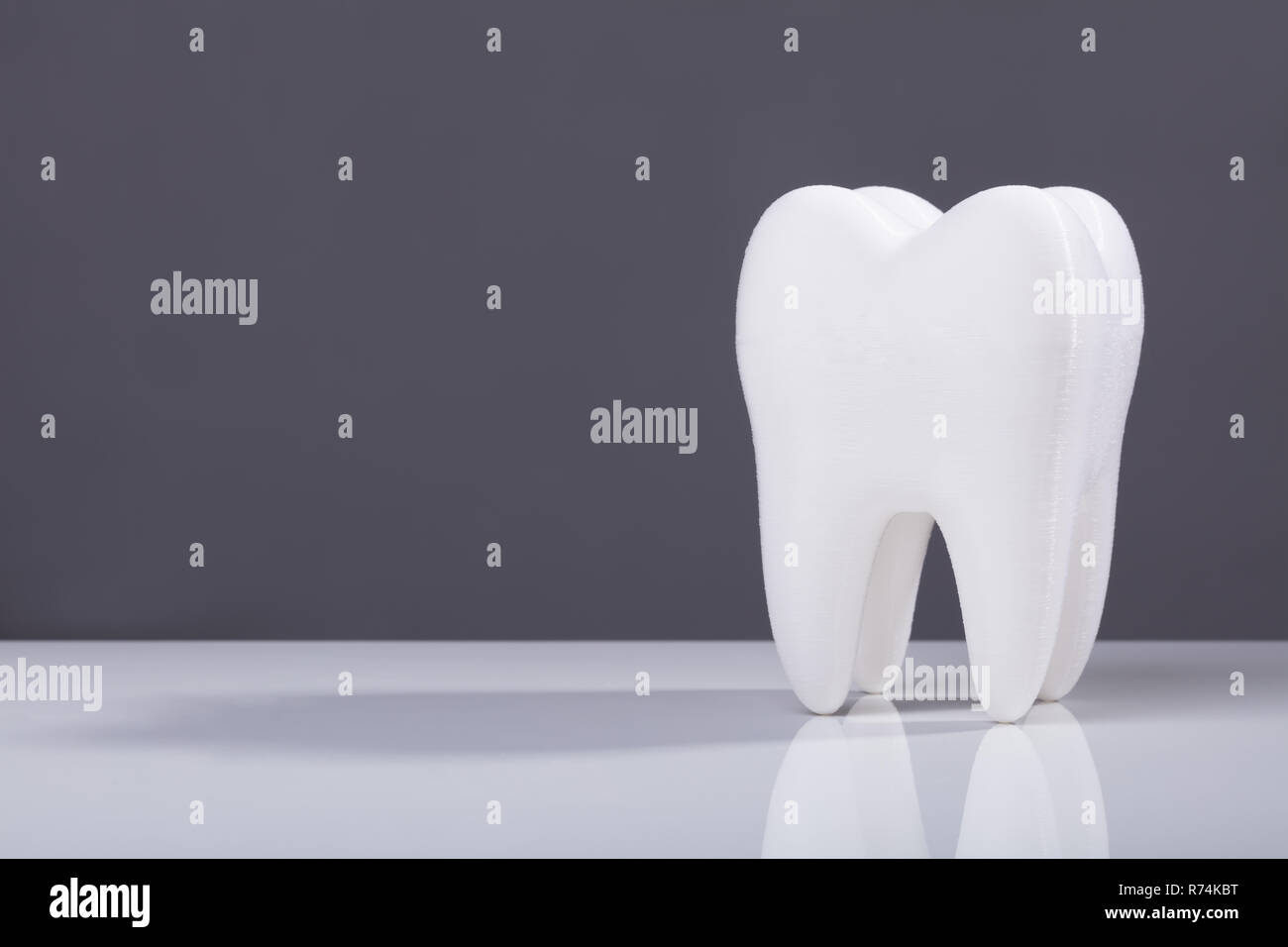 Single White Tooth On Grey Background Stock Photo - Alamy