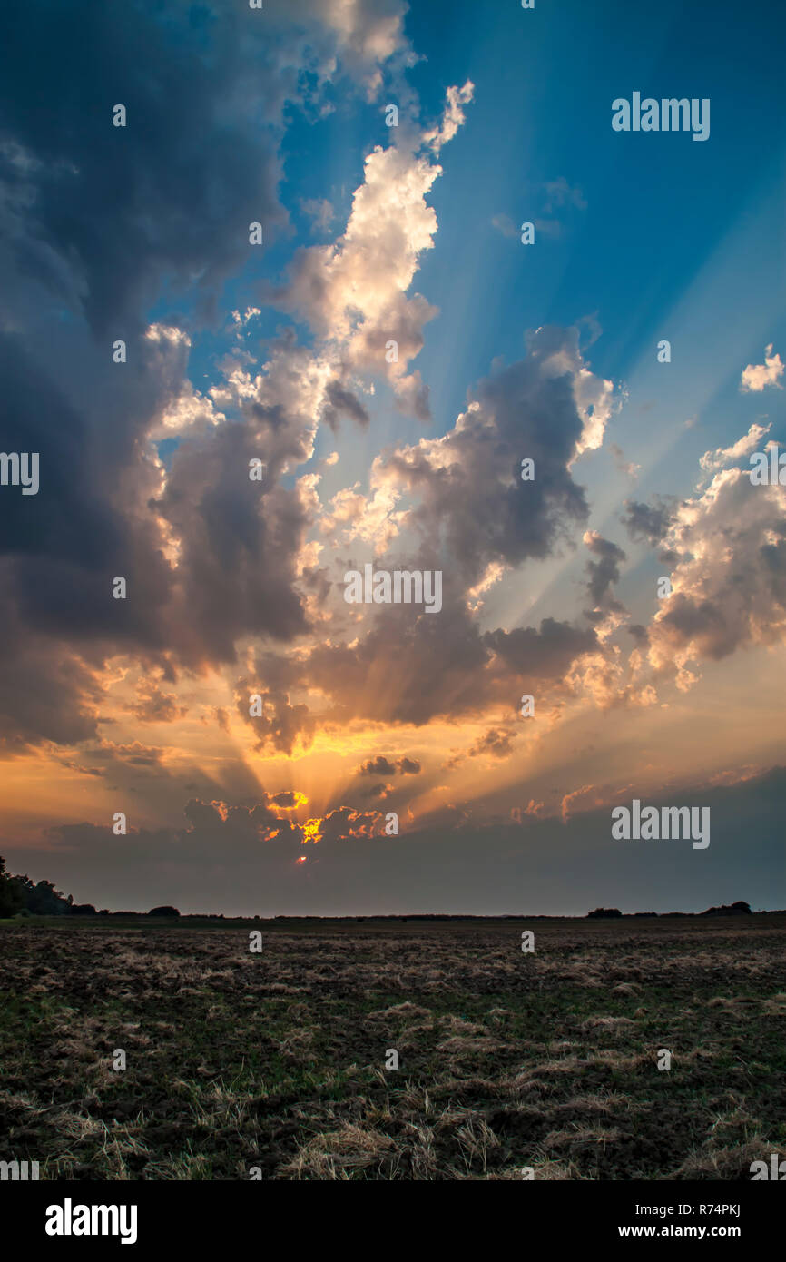 Inspiring sunset over cultivated land with dramatic sky, clouds and ...