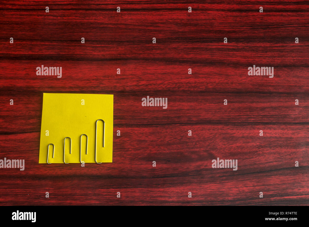 Paper clips attached by size on a yellow note Stock Photo - Alamy