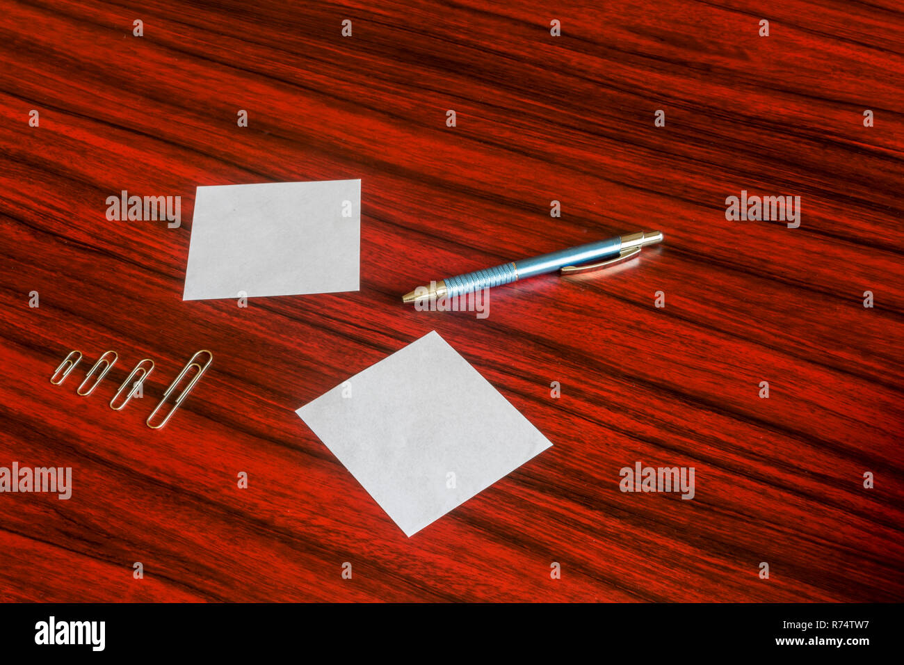 Paper clips arranged by size on a desk with sticky notes and pen aside ...