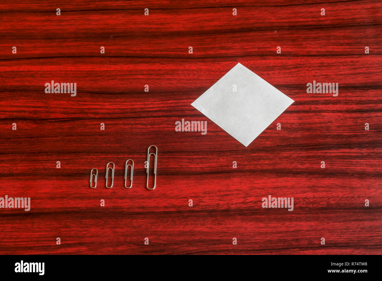 Paper clips arranged by size on a desk with sticky notes aside Stock ...