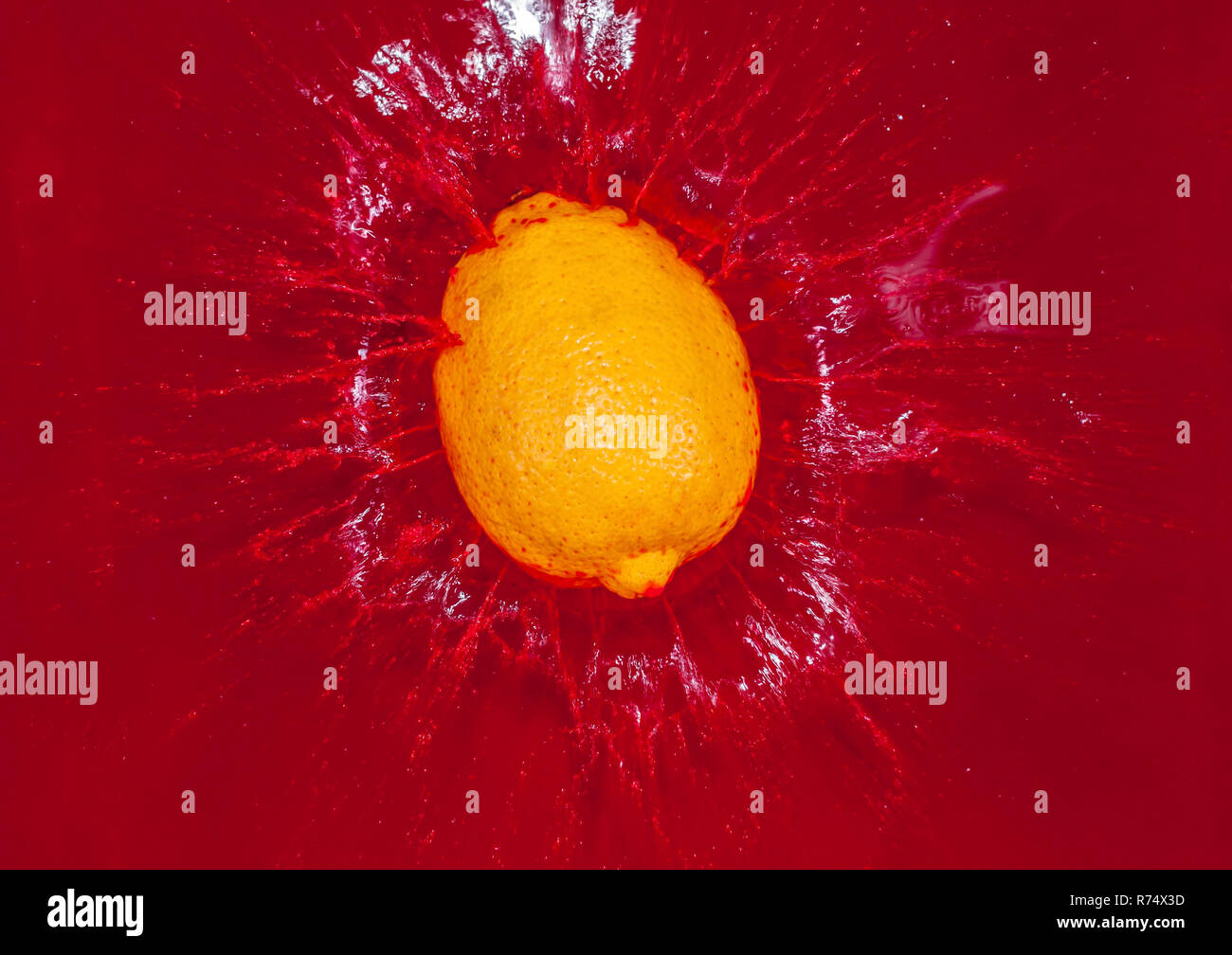 Yellow lemon falling into red water and creating a splash Stock Photo ...