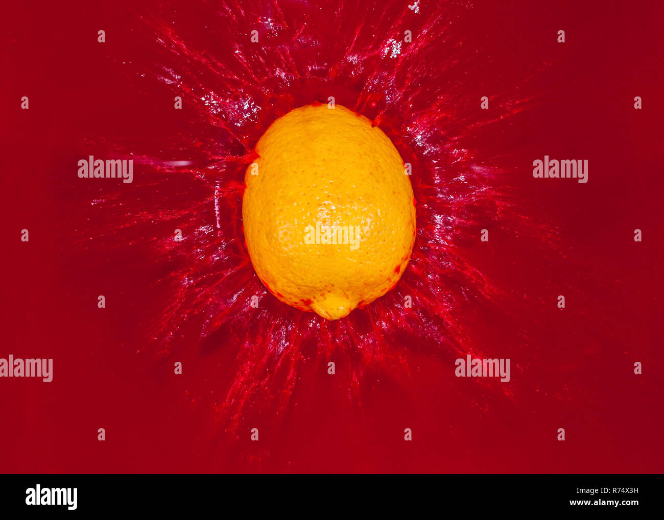 Yellow lemon falling into red water and creating a splash Stock Photo ...