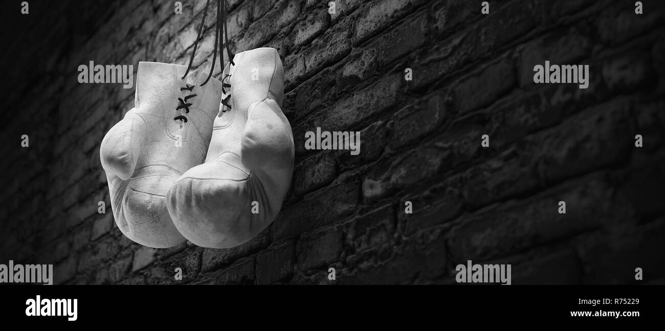 Old white boxing gloves hang on nail on brick wall with copy space for ...
