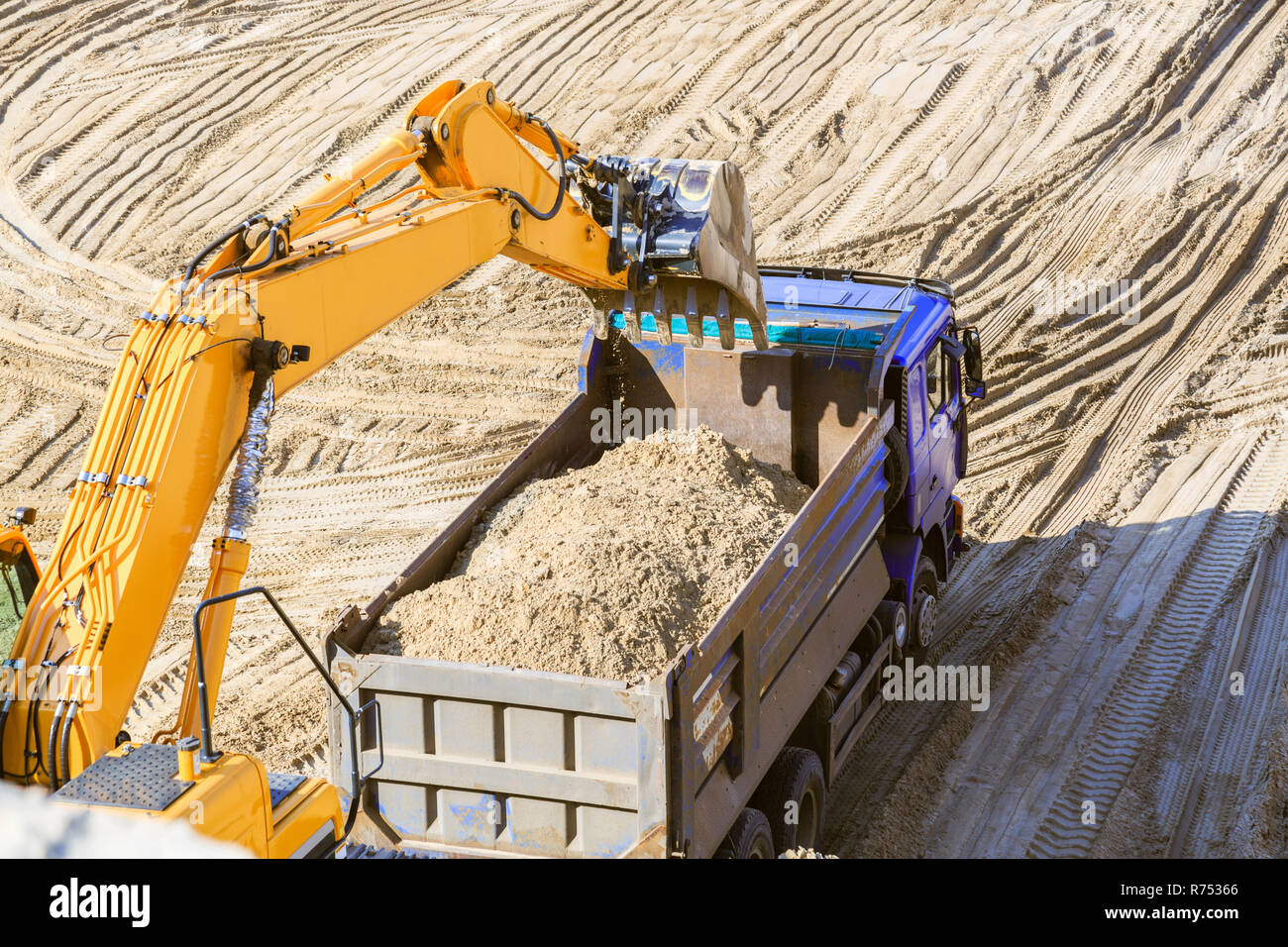 Work of the excavator and truck at a sand quarry. Excavator loading ...