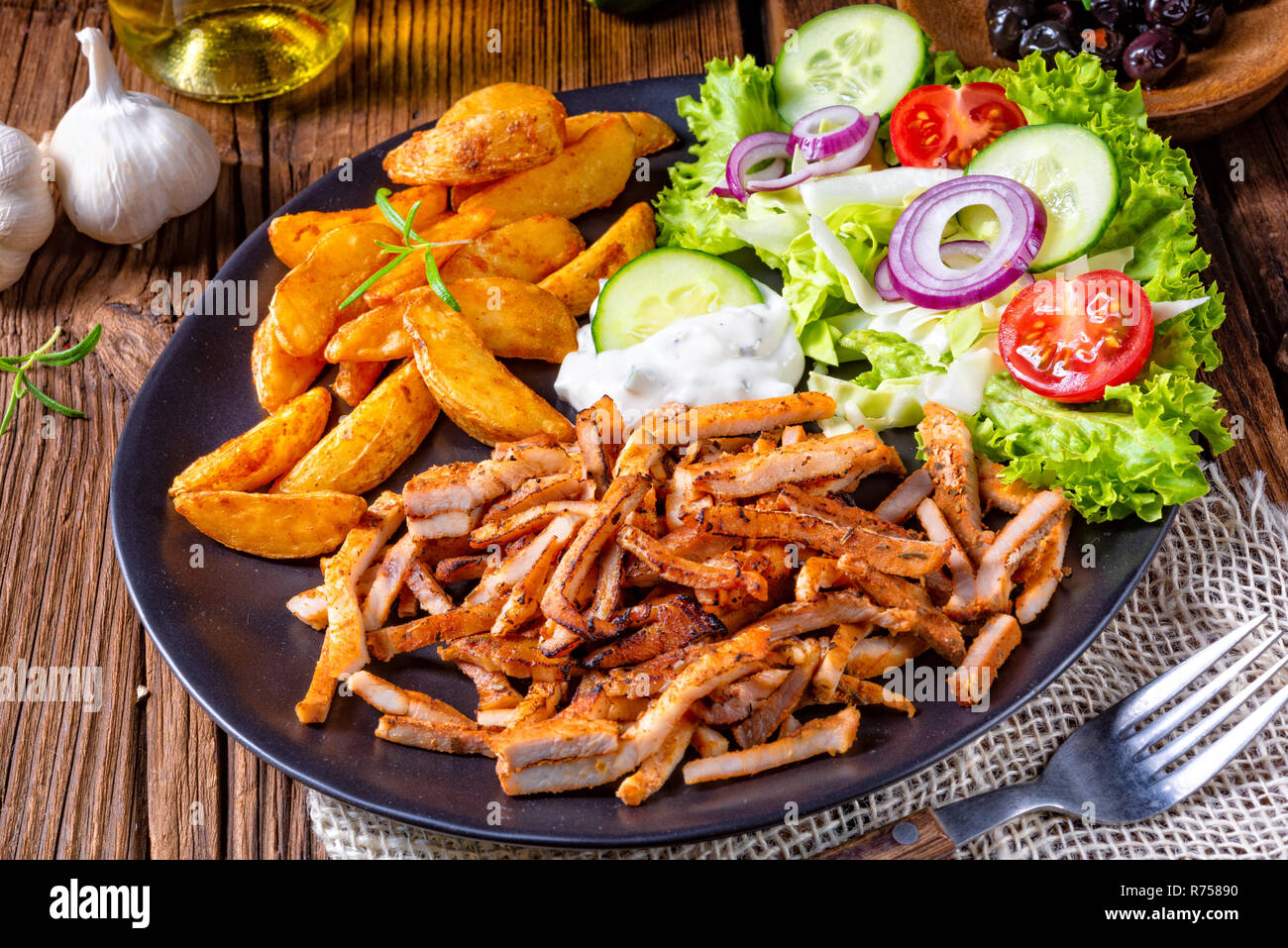rustic gyros plate with green salad and potato wedges Stock Photo - Alamy