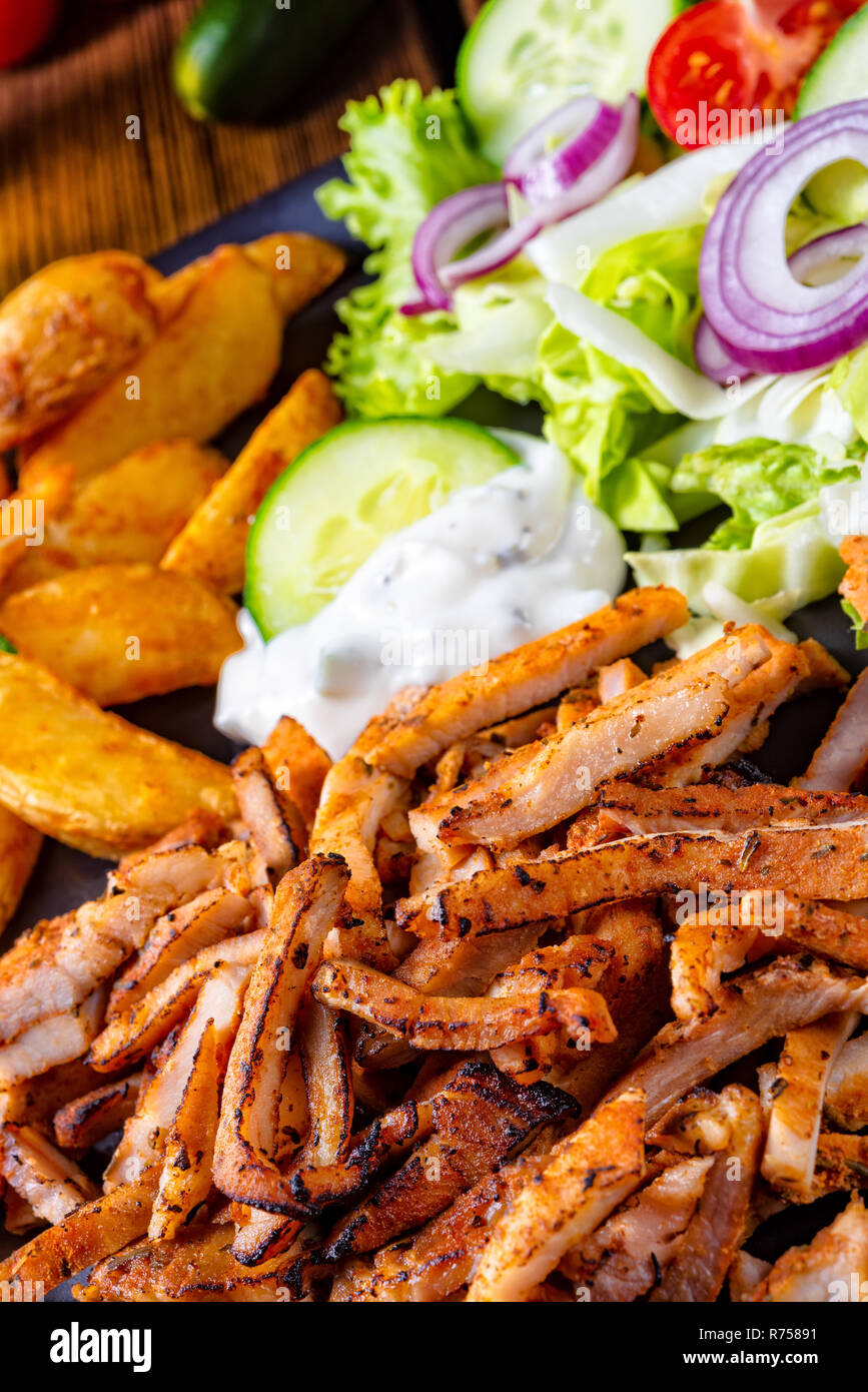 rustic gyros plate with green salad and potato wedges Stock Photo - Alamy