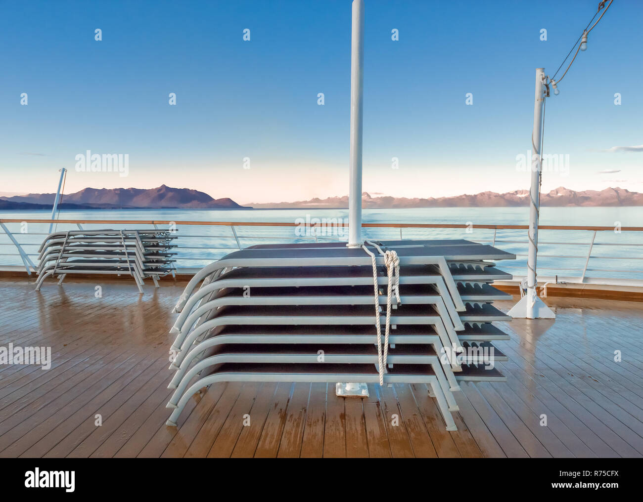 Stack of exterior plastic lounge chairs on stern of cruise ship, in the ...