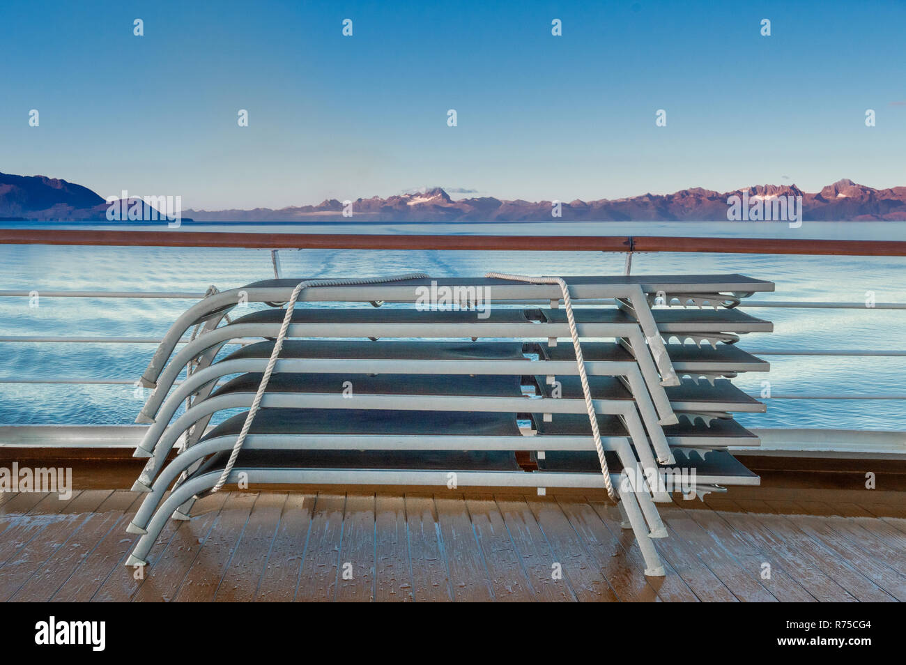 Stack of exterior plastic lounge chairs on stern of cruise ship, in the ...