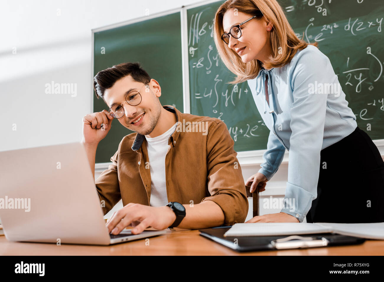Student in glasses looking at laptop with female teacher Stock Photo ...