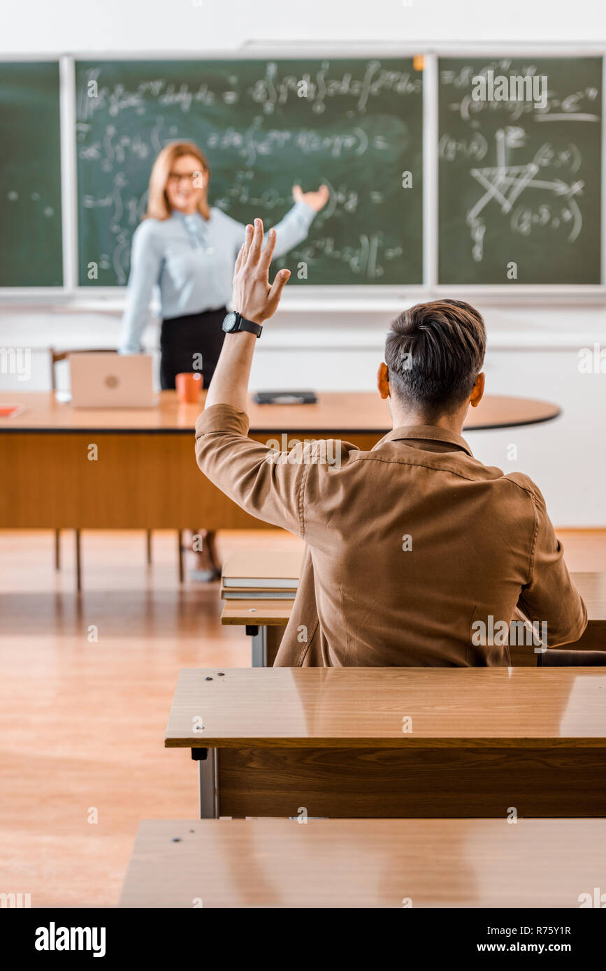 Selective focus of male student raising hand in classroom Stock Photo ...