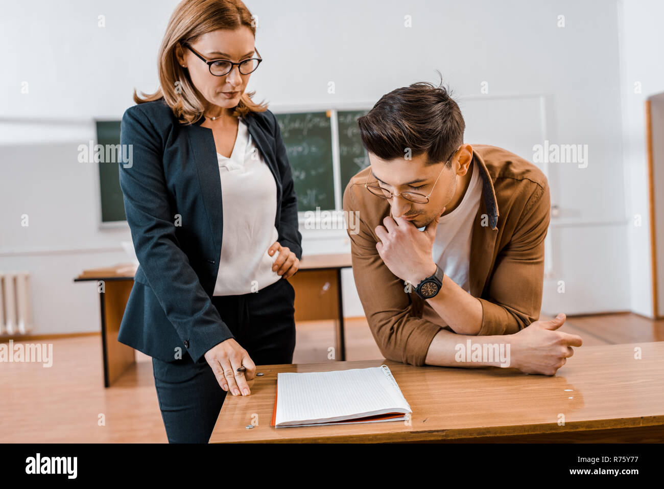 serious female teacher and male student during exam in classroom Stock ...