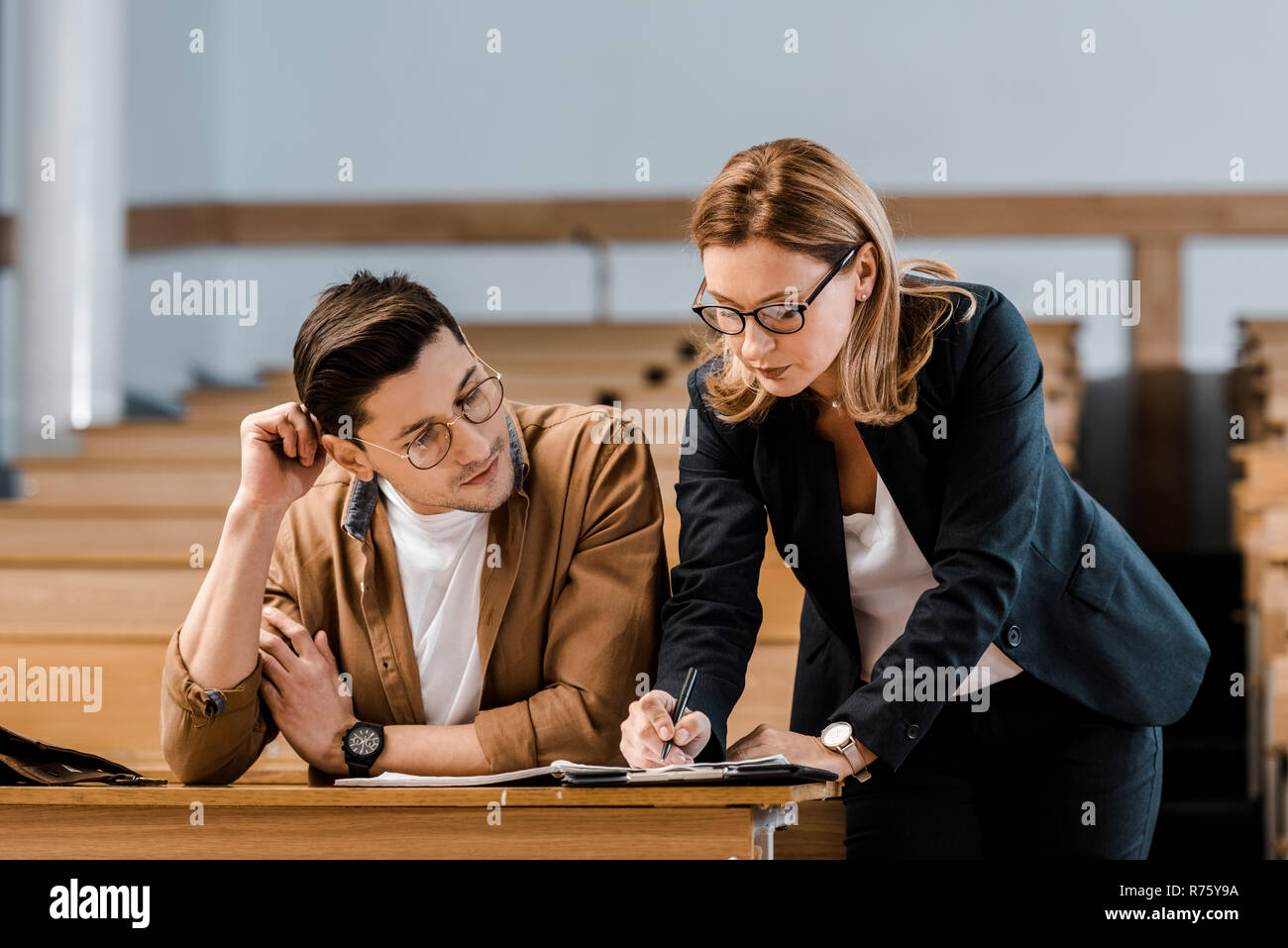 female teacher in glasses checking exam results of male student in ...
